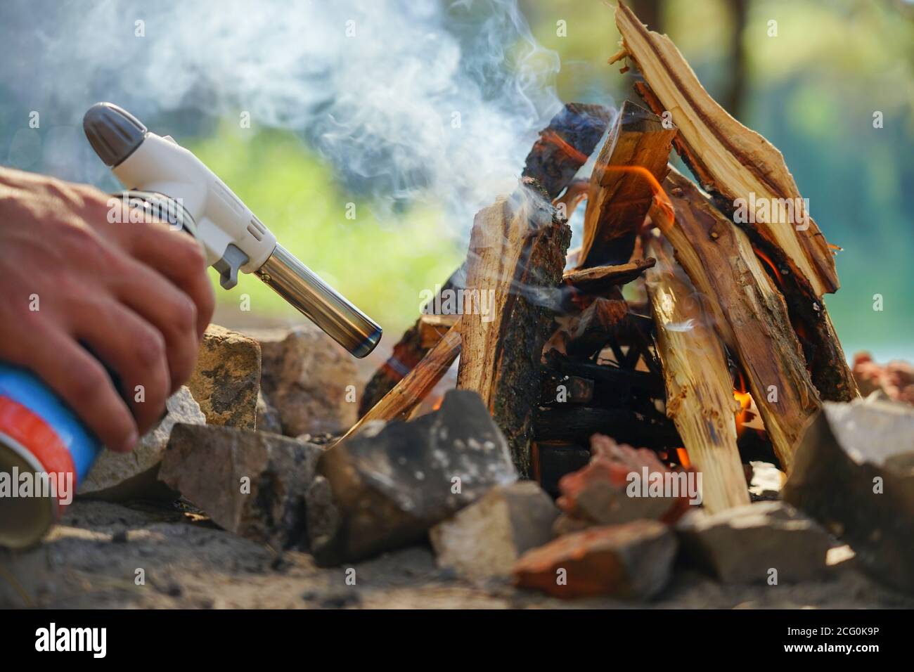 Hand holds manul gas burner near firewood Stock Photo - Alamy