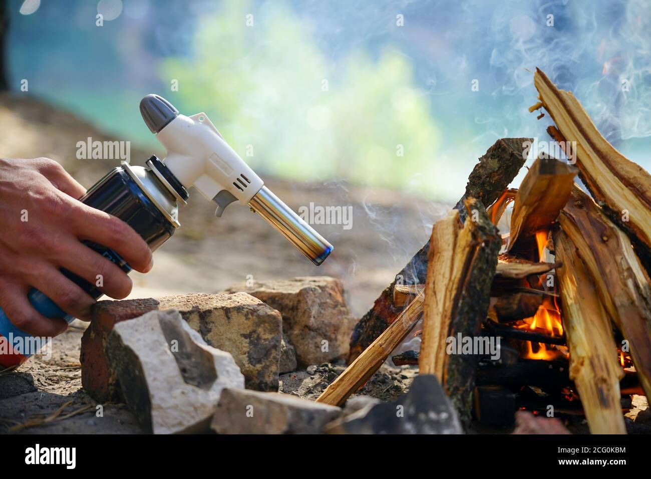 Hand holds manul gas burner near firewood Stock Photo - Alamy