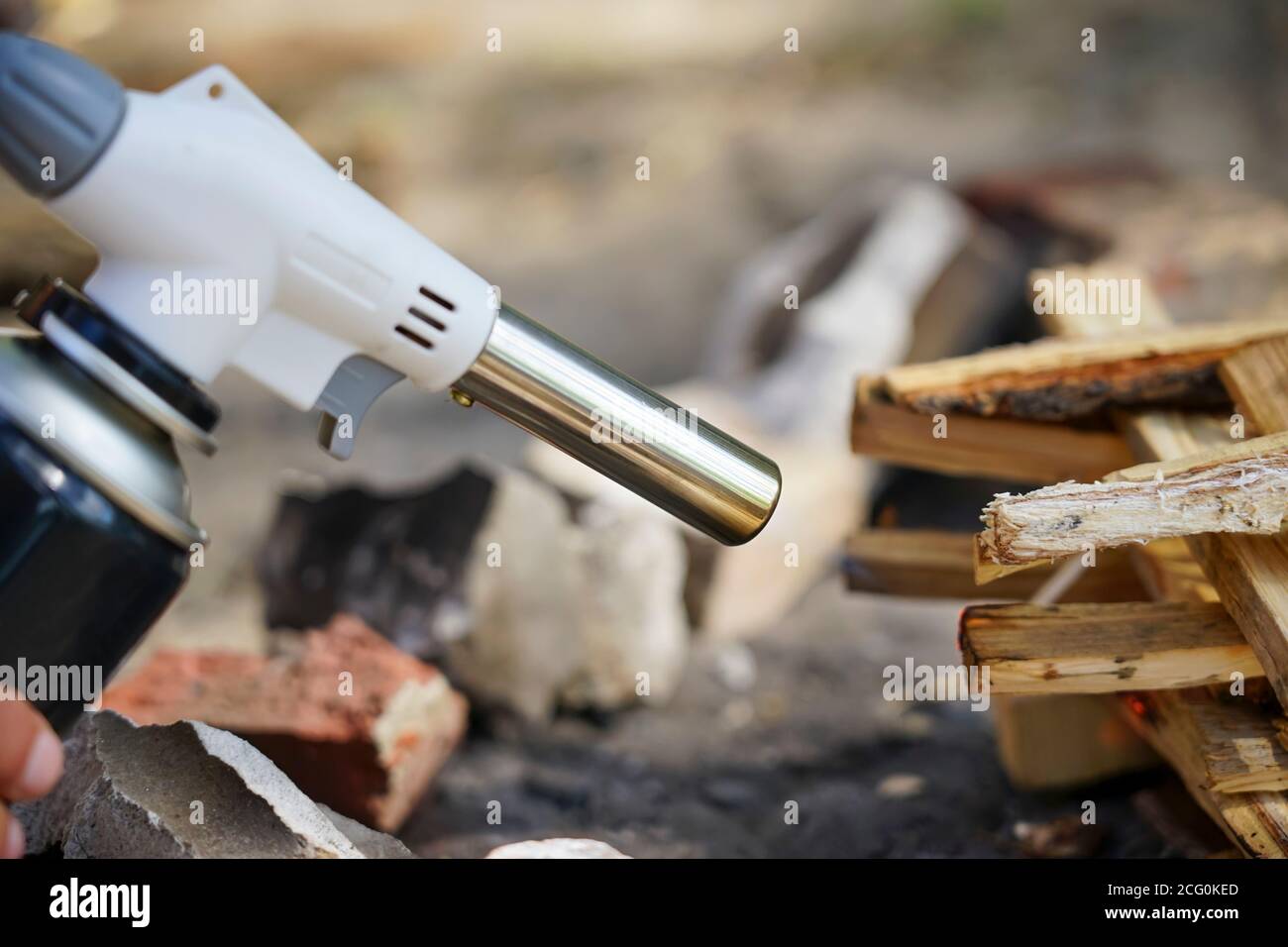 Hand holds manul gas burner near firewood Stock Photo - Alamy