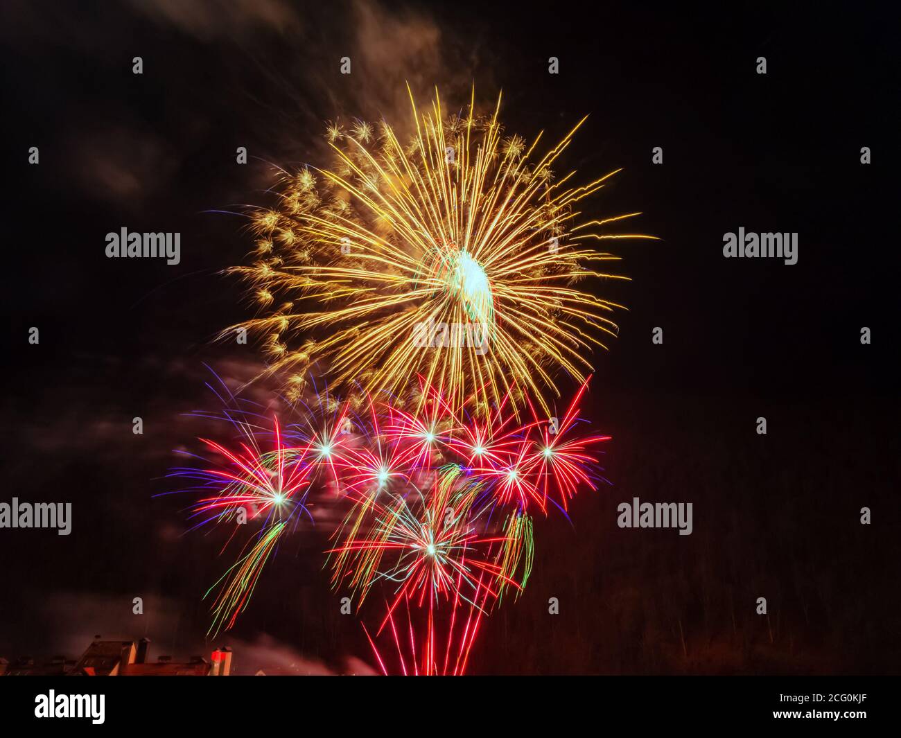 Large golden flash of fireworks and many small flashes in red with ...