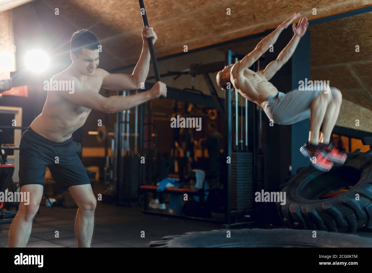 two Male fitness models training workout witth heavy and big tire and ...