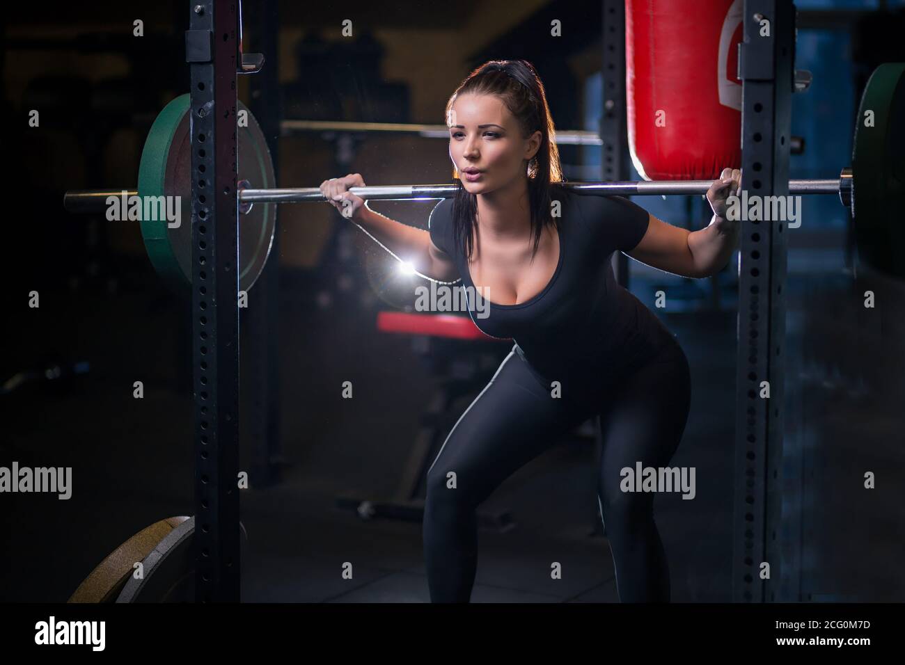 Female working out in a gym doing squats. Young woman working out using ...