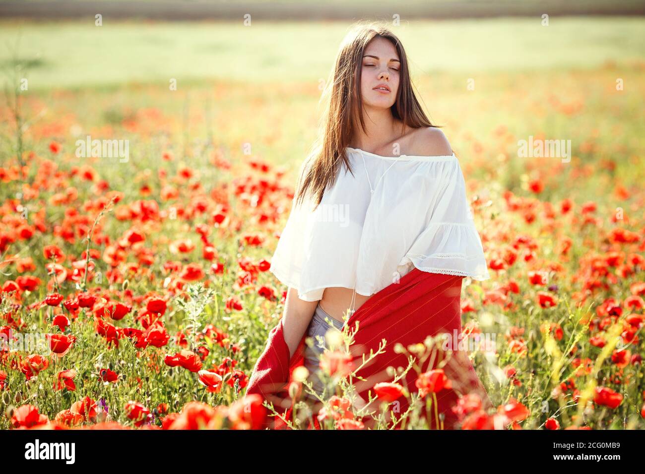 young beautiful woman walking through a poppy field in summer. Close up ...