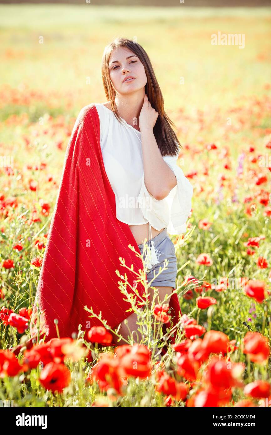 young beautiful woman walking through a poppy field in summer. Close up ...