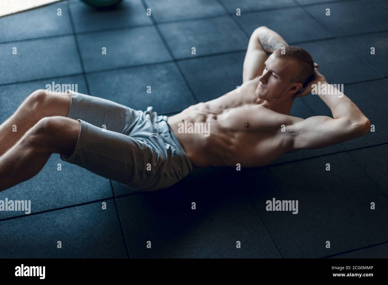 Group of athletic adult men performing sit up exercises to strengthen ...