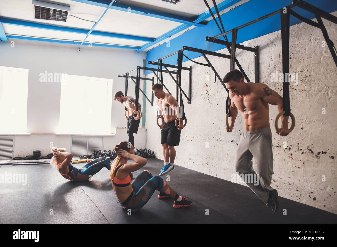 tree attractive young male and female adults doing pull ups on bar in ...