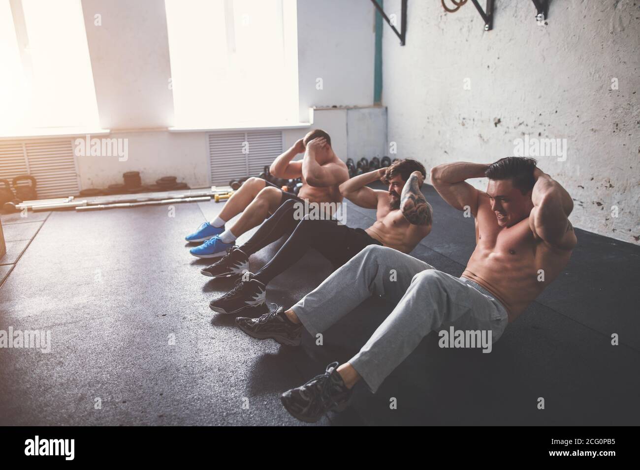 Group of athletic adult men and women performing sit up exercises to ...