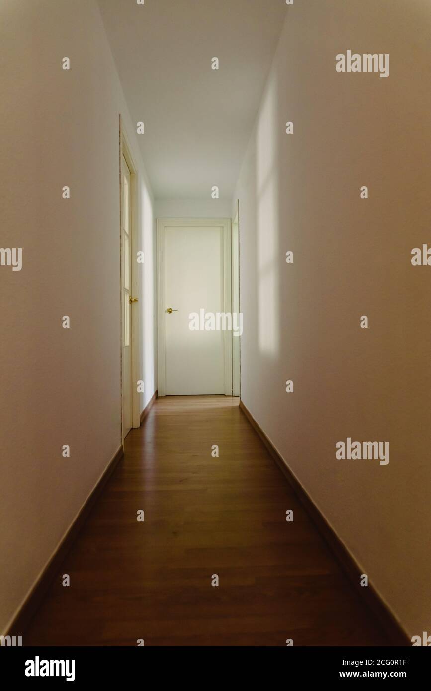 Scary light-walled hallway with a closed door illuminated by the dim ...