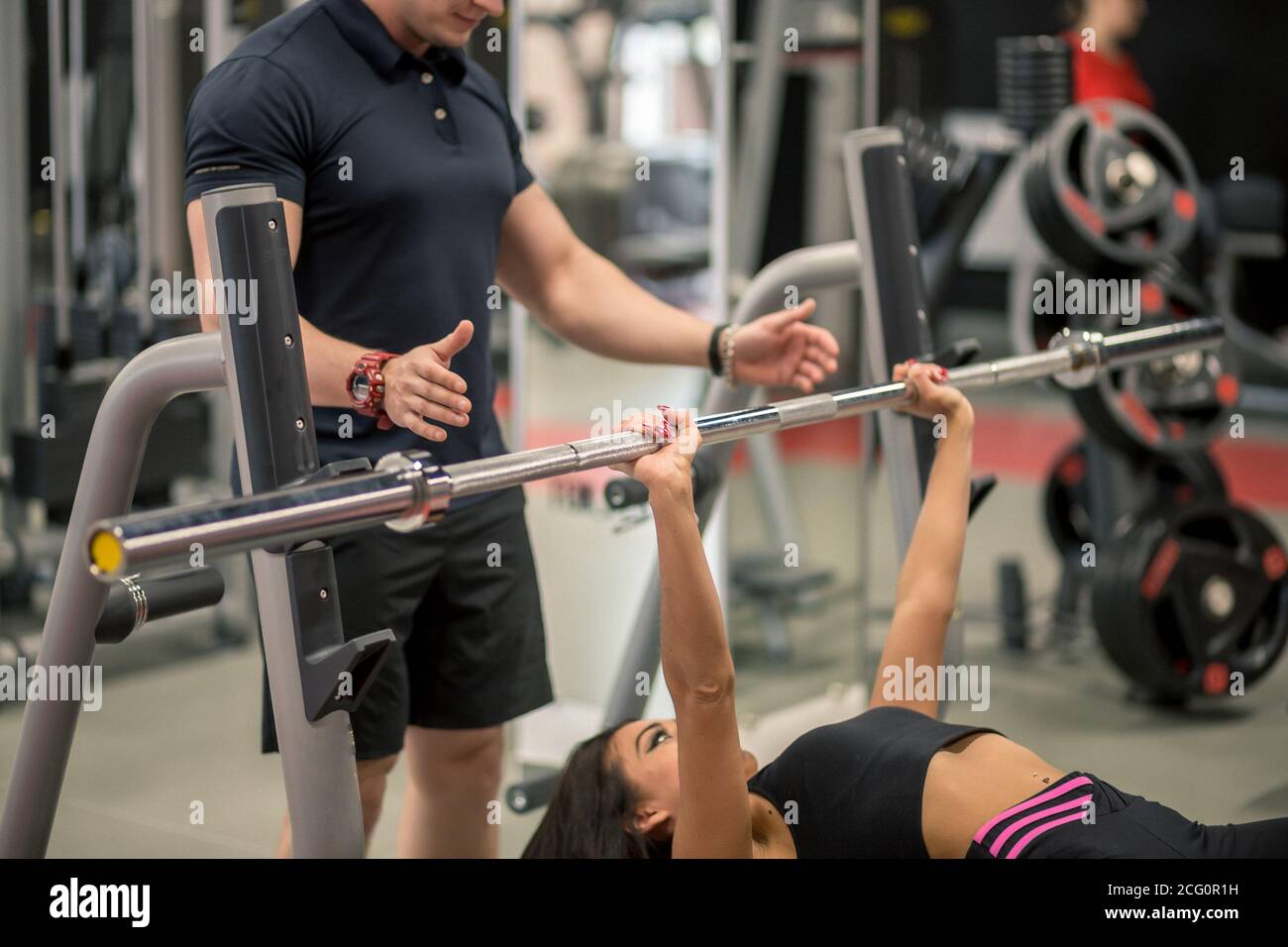 Personal trainer and fit woman working with barbell Stock Photo - Alamy