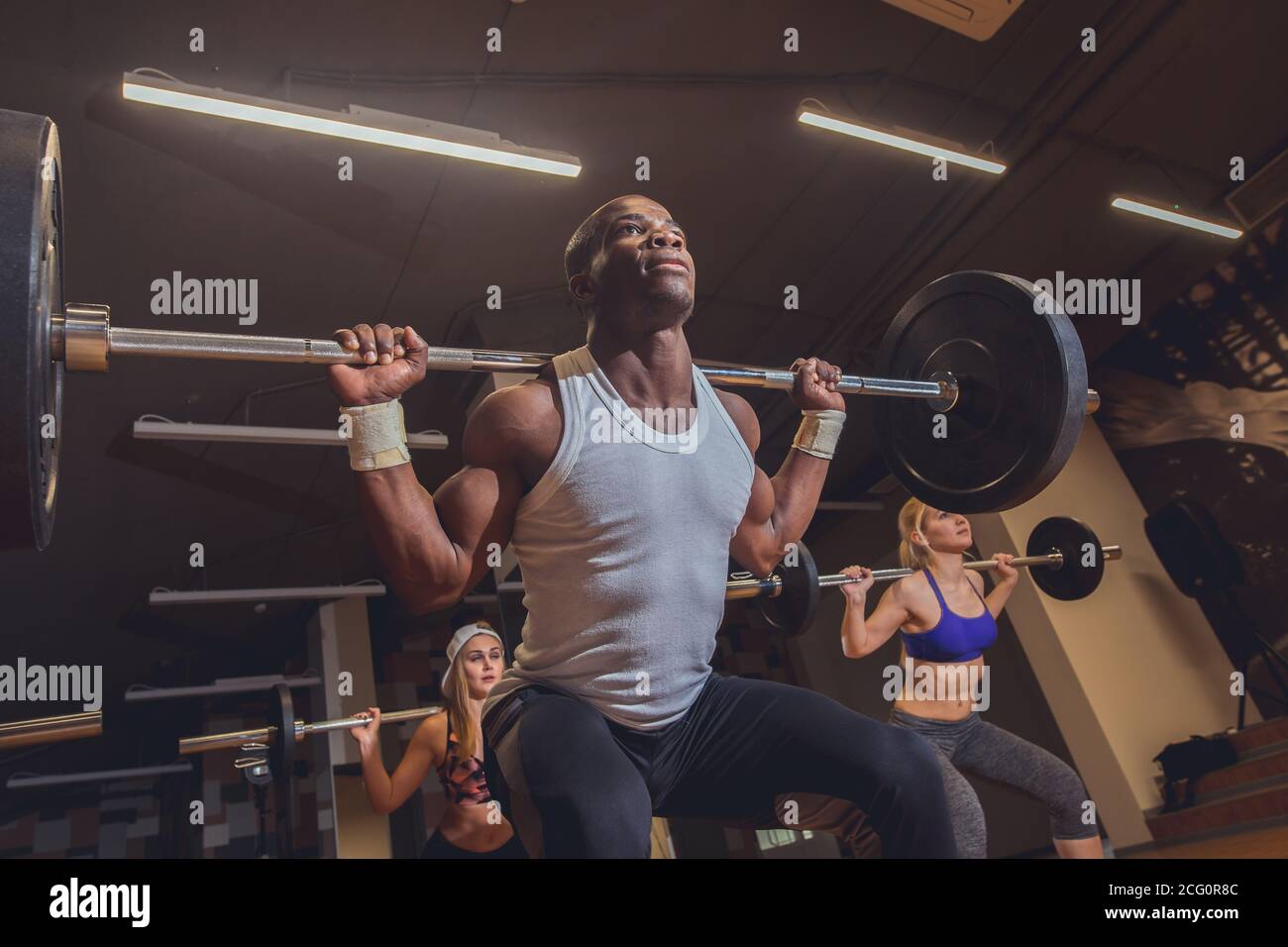 group of young athletes with African trainer doing squats with a ...