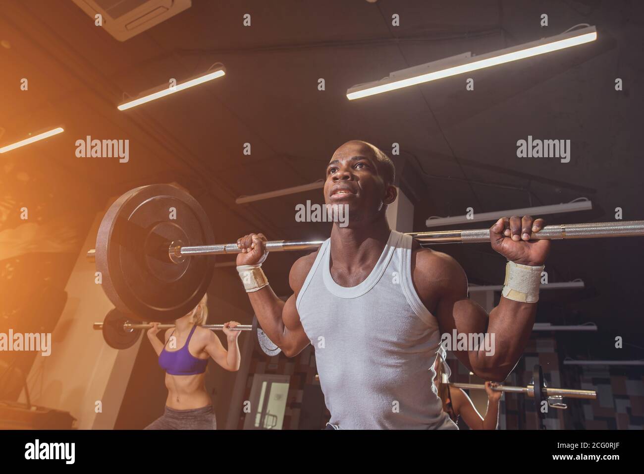 group of young athletes with African trainer doing squats with a ...
