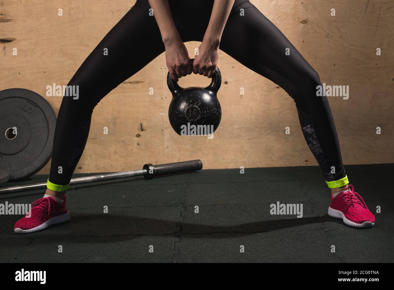 Athletic woman exercising with kettle bell while being in squat ...