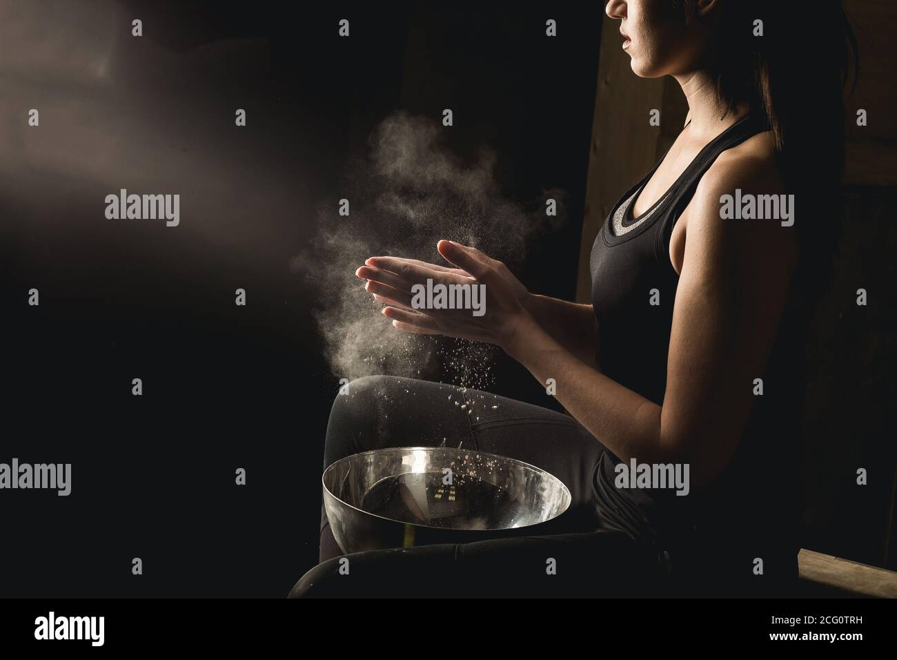 Female fitness model clapping hands with talc powder in a gym just ...