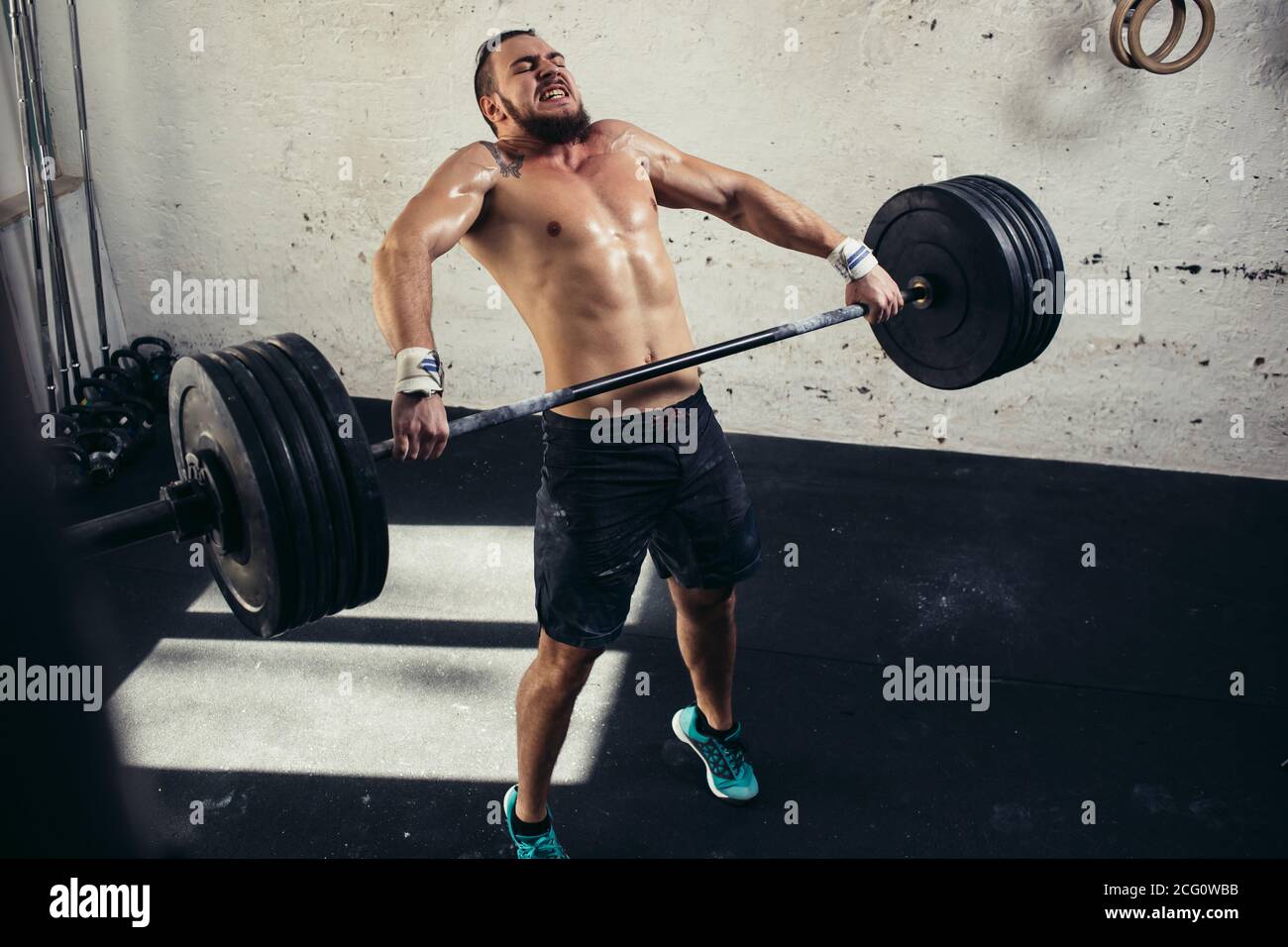 Full length image of tough young man exercising with barbell ...