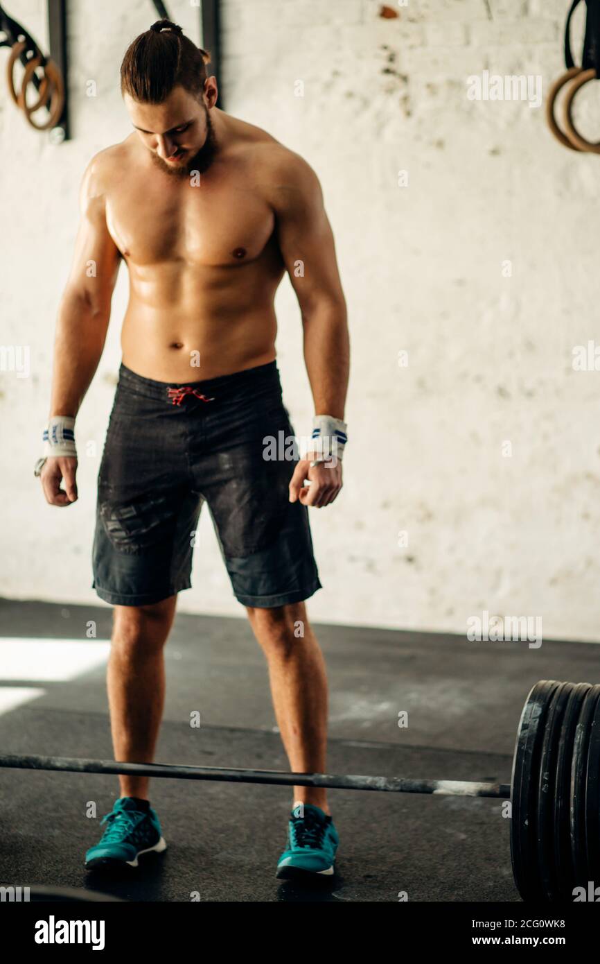 Full length portrait of muscular young man standing at gym with ...