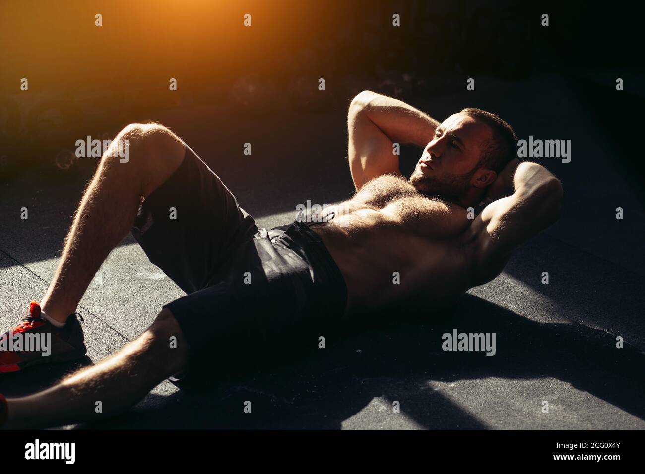 Side view of fit young man doing pilates, working on abdominal muscles ...