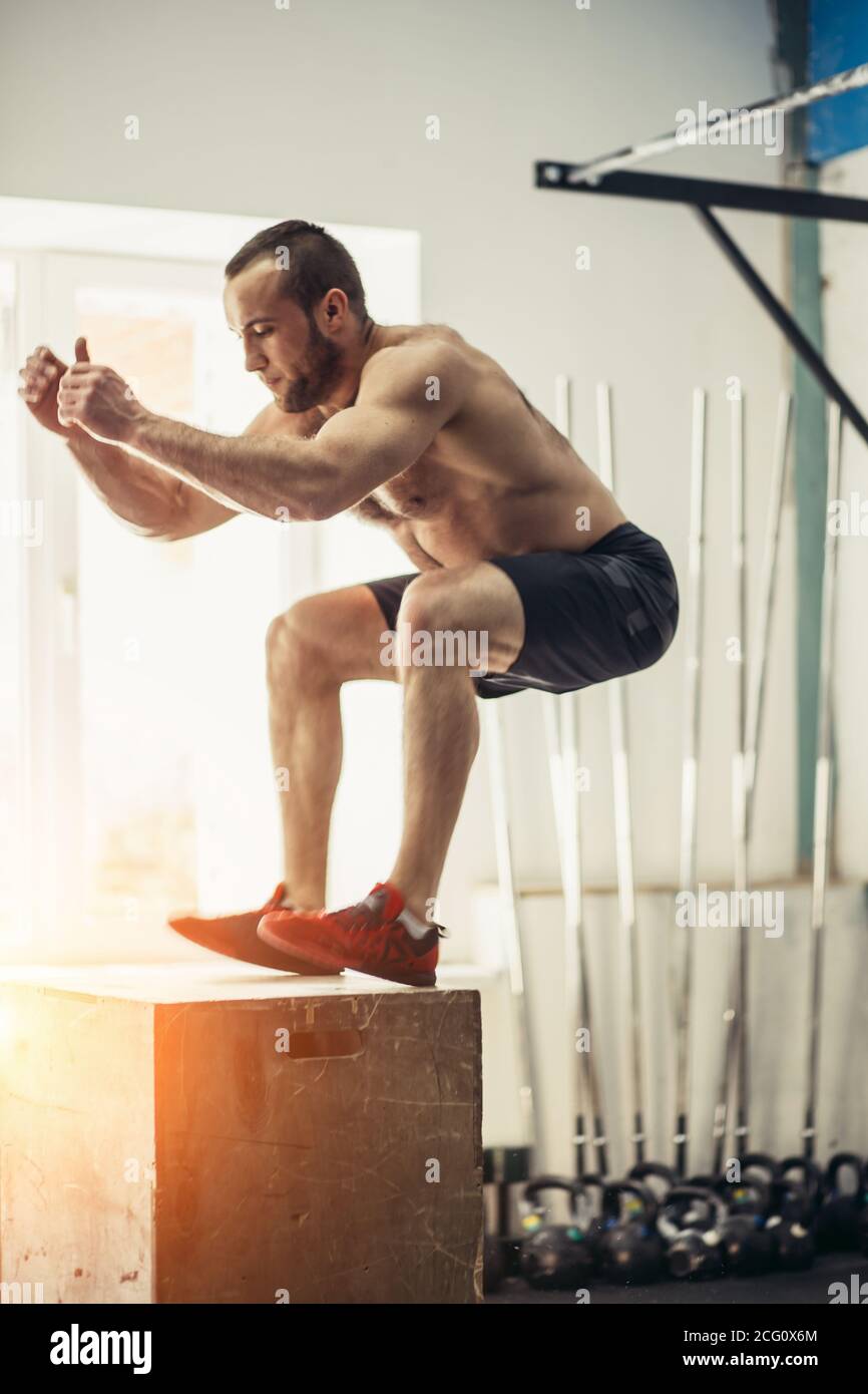 Fit young people doing box jumps in a gym Stock Photo - Alamy