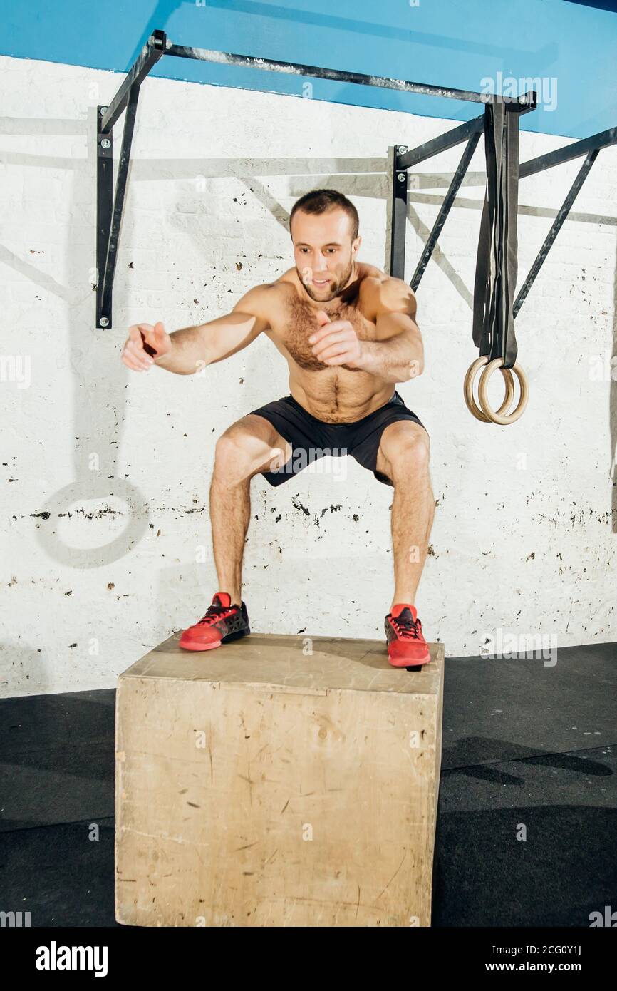 Fit young people doing box jumps in a gym Stock Photo - Alamy