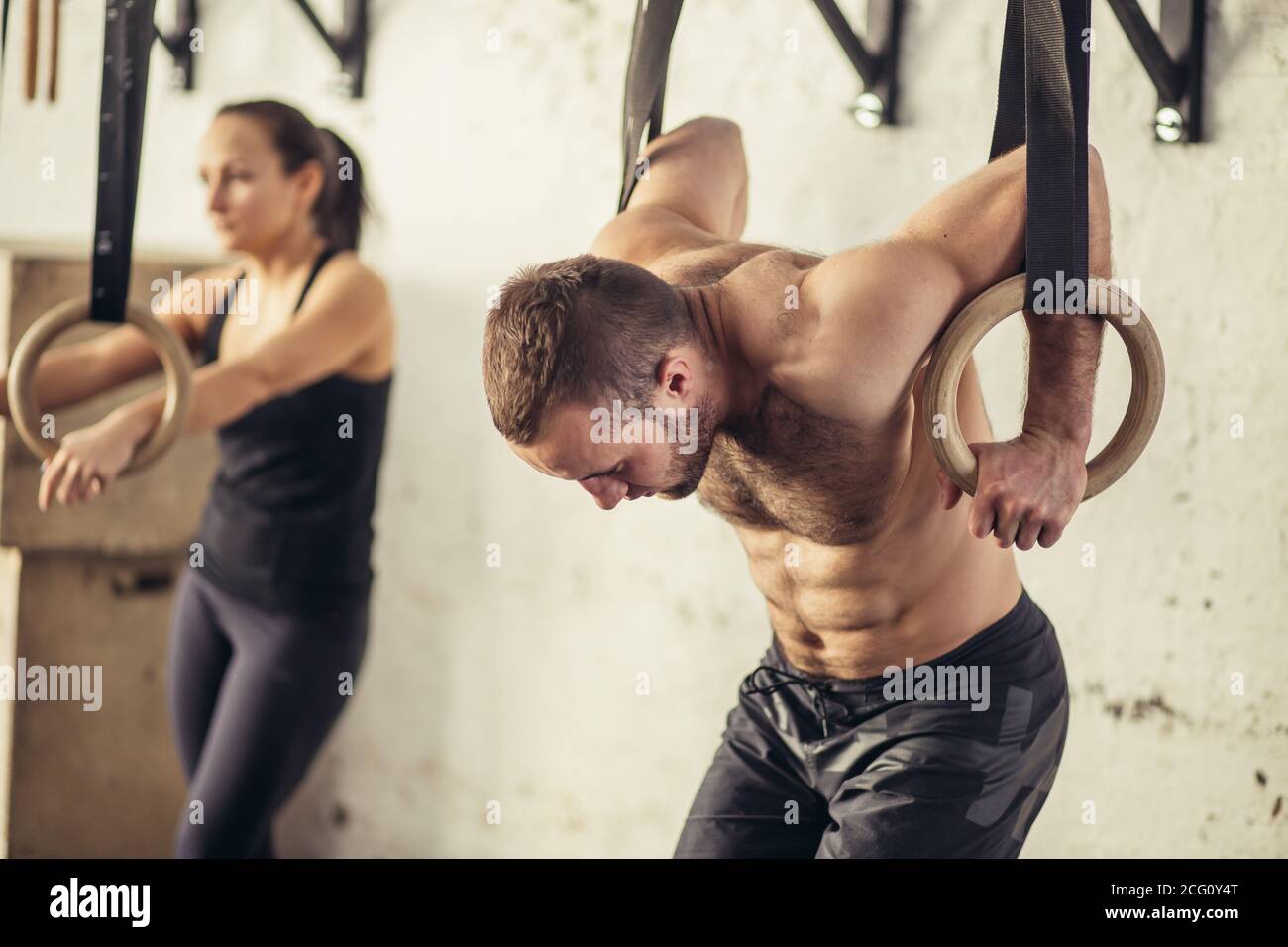 Fitness handsome man doing dipping exercise using rings in the gym ...