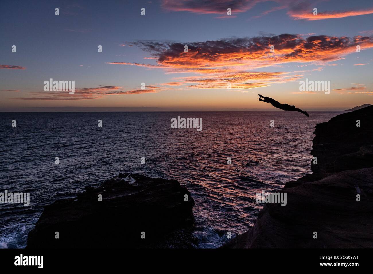 Cliff diver over the ocean at sunset in Hawaii Stock Photo - Alamy