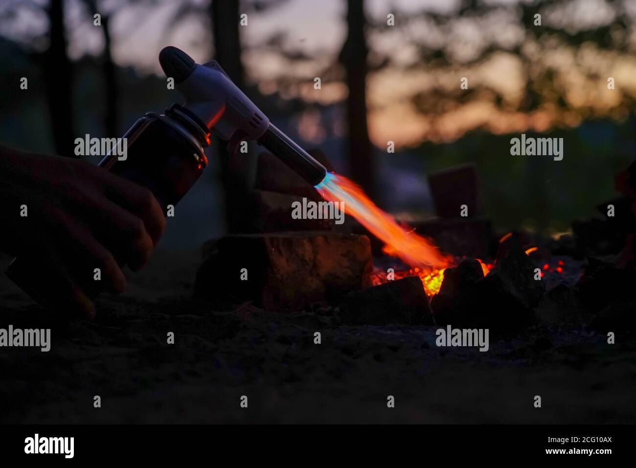 Hand holds manul gas burner near firewood at night Stock Photo - Alamy