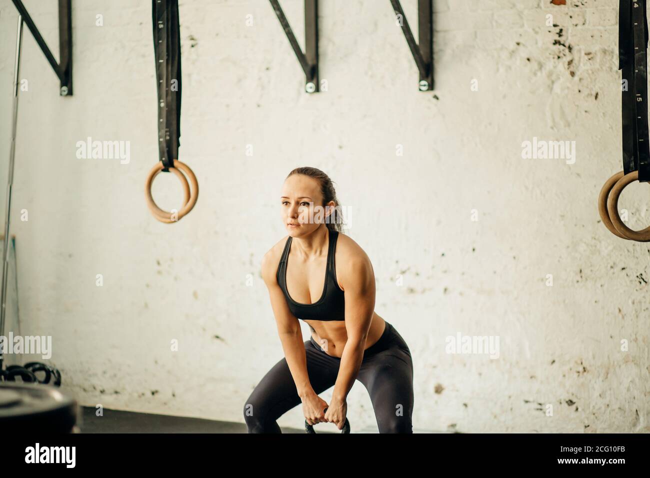 Athletic woman exercising with kettle bell while being in squat ...