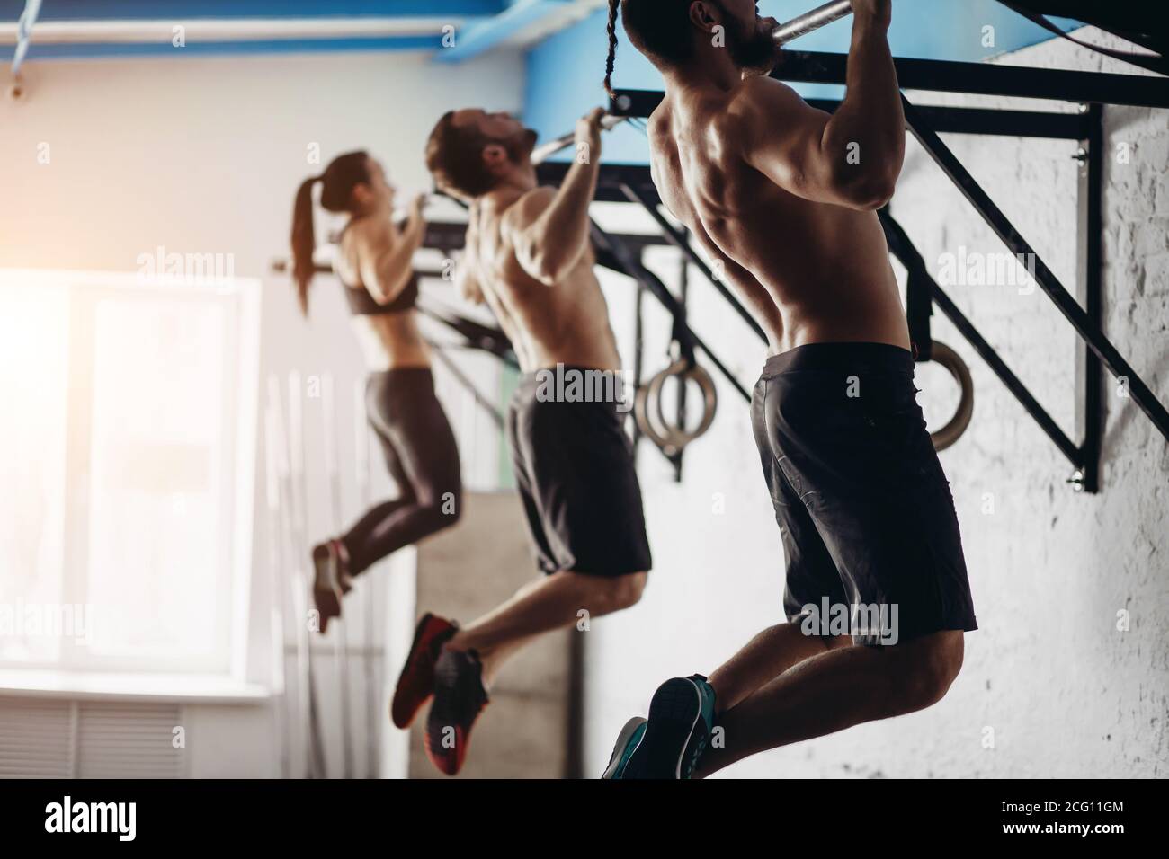 Group of six attractive young male and female adults doing pull ups on ...