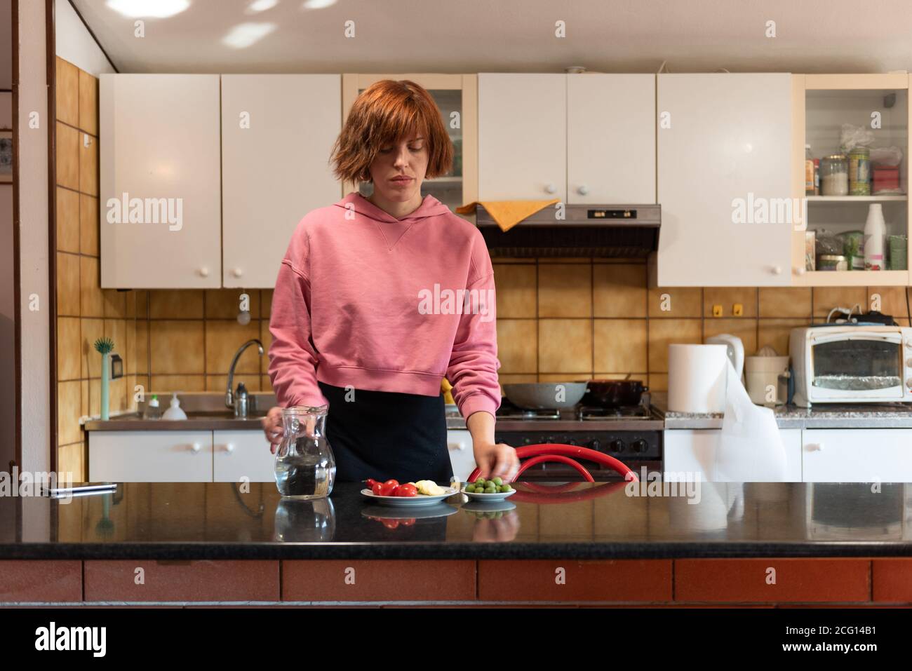 Girl in the kitchen with olives, tomatoes and water. Usual environment ...