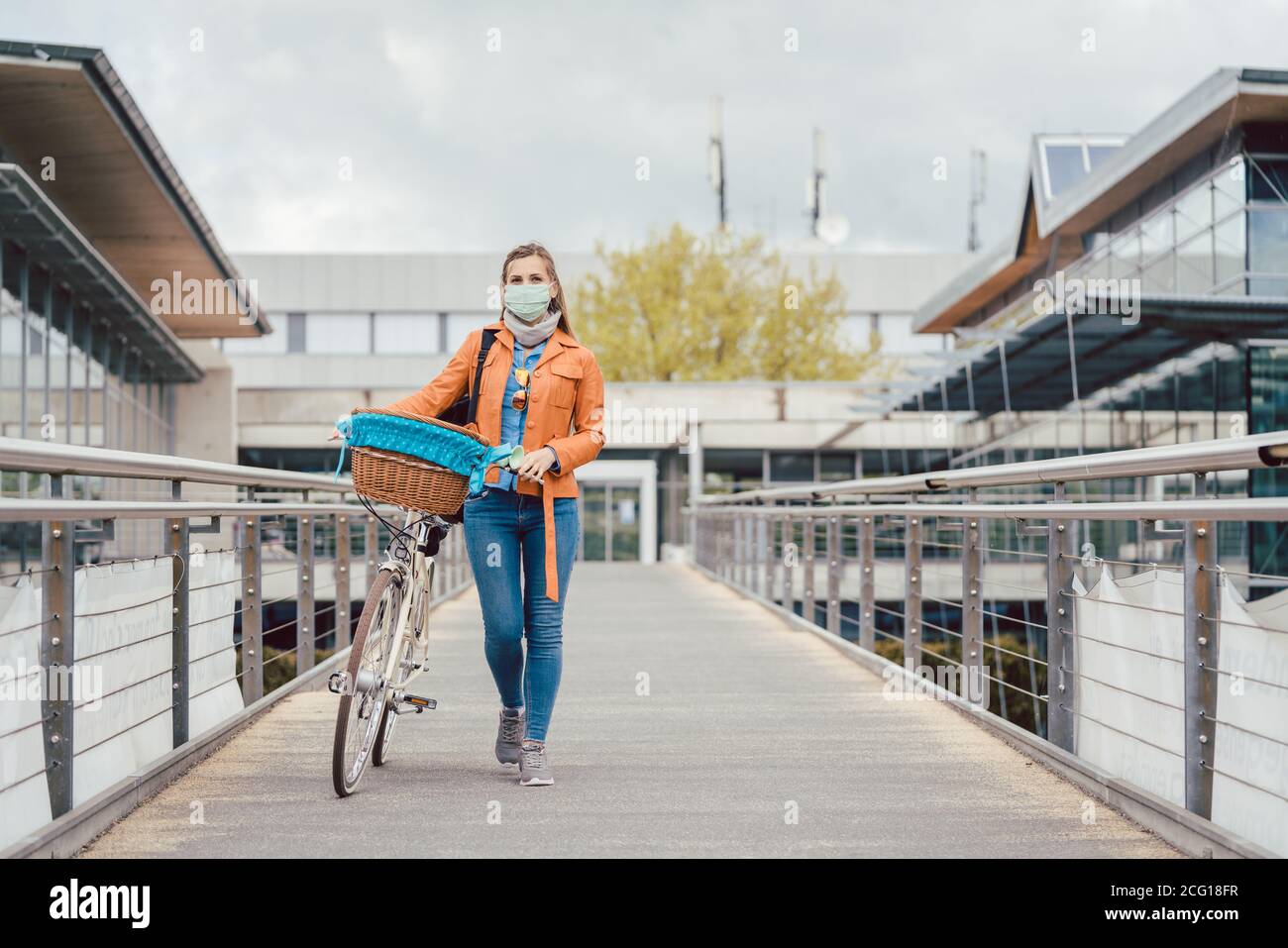 Woman with face mask pushing her bike over a bridge Stock Photo - Alamy
