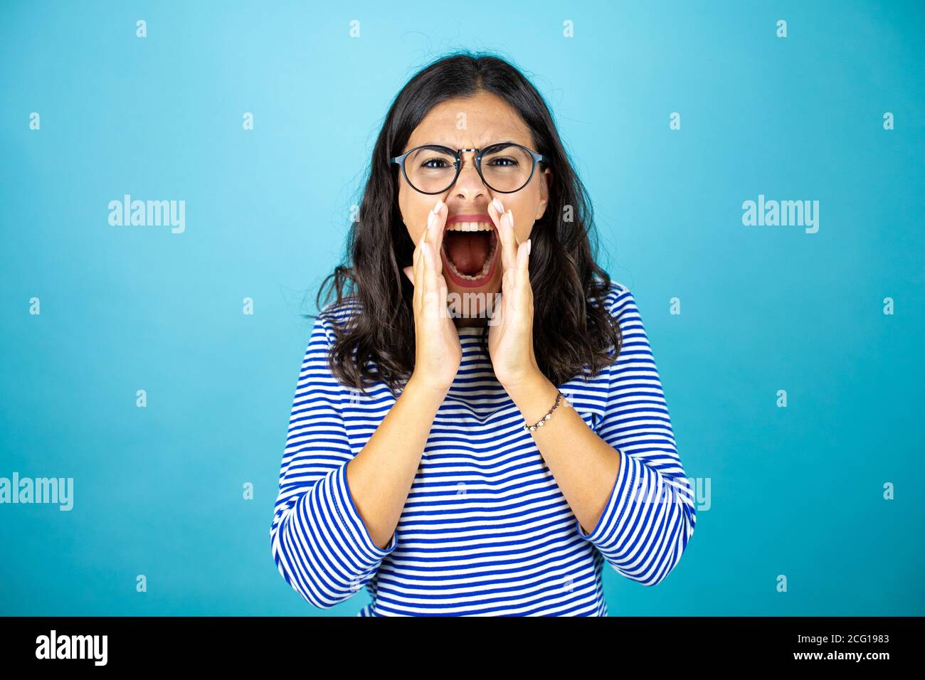 Pretty woman wearing glasses standing over insolated blue background ...