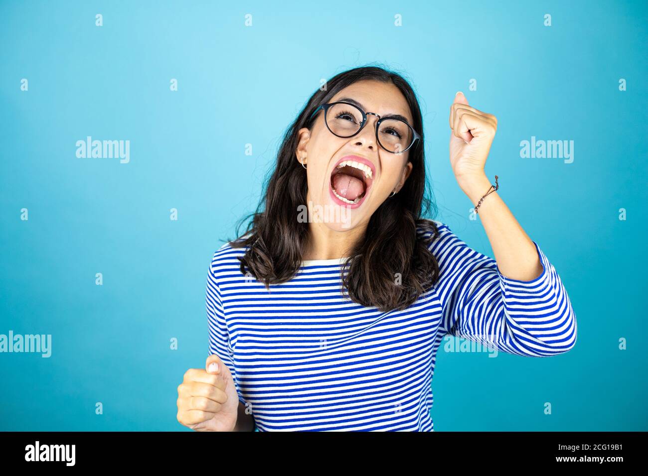 Pretty woman wearing glasses standing over insolated blue background ...