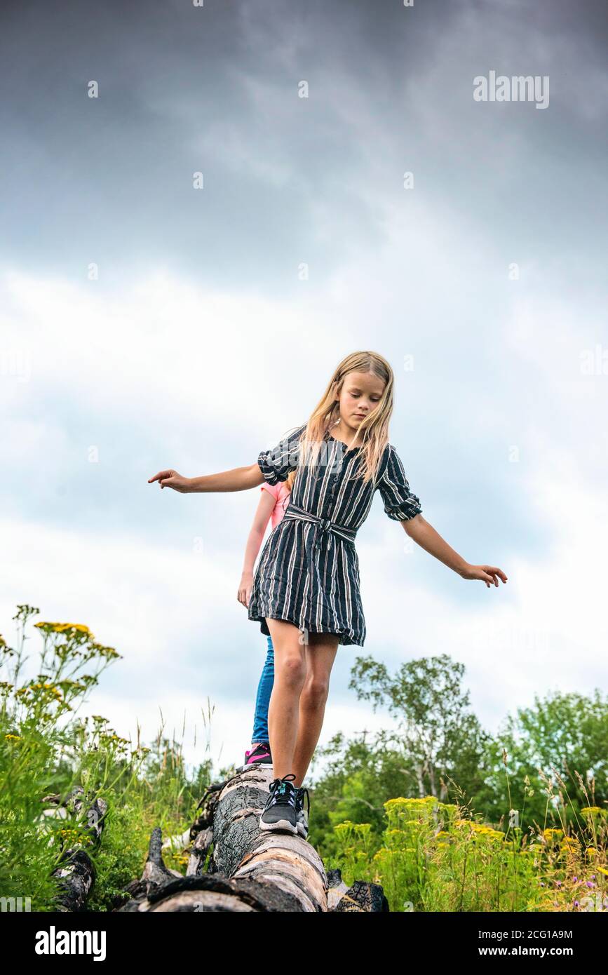 Two Young Girls Walking on a Log Stock Photo - Alamy
