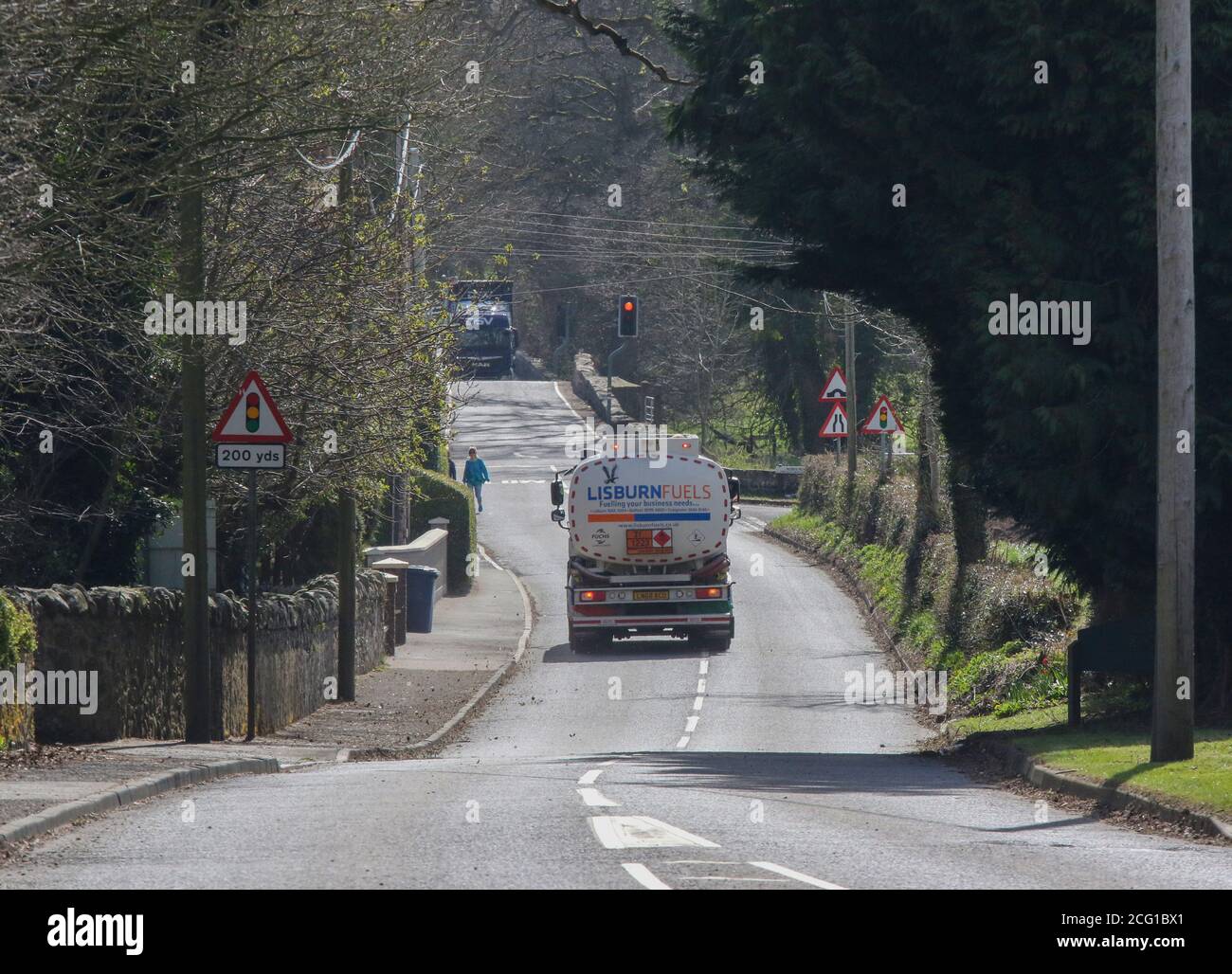 Oil tanker going downhill on rural country road towards humpback stone ...
