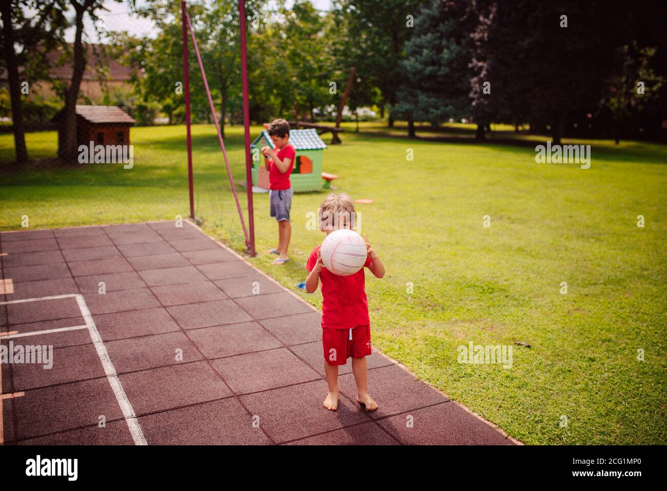 Two little caucasian boys in red T-shirts throw a ball on the ...