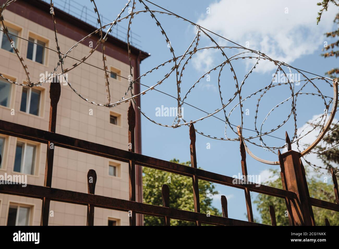 Building wall behind barbed wire barrier with beautiful heavenly clouds ...