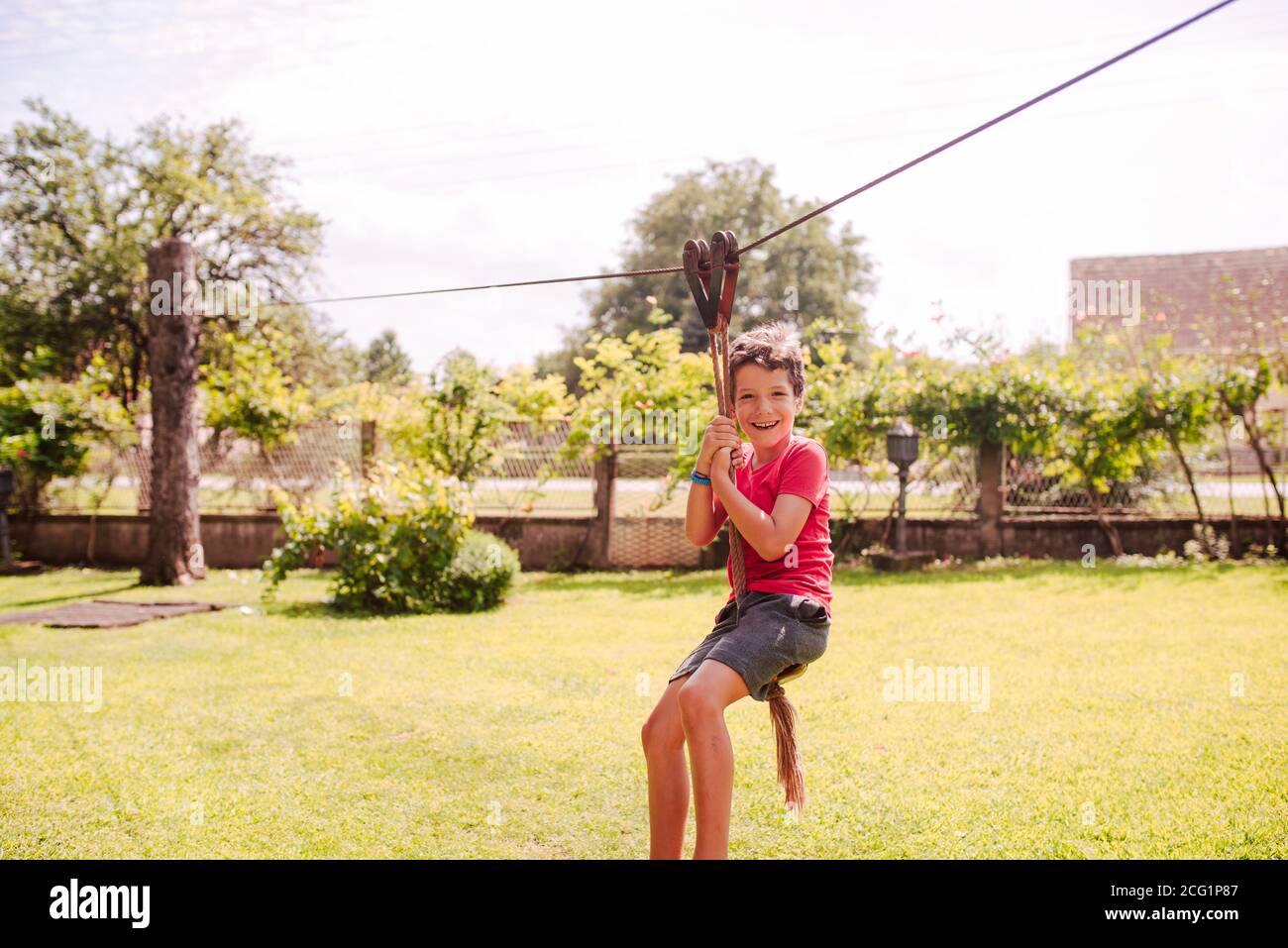 A beautiful little caucasian boy on a zip line for children in the park ...
