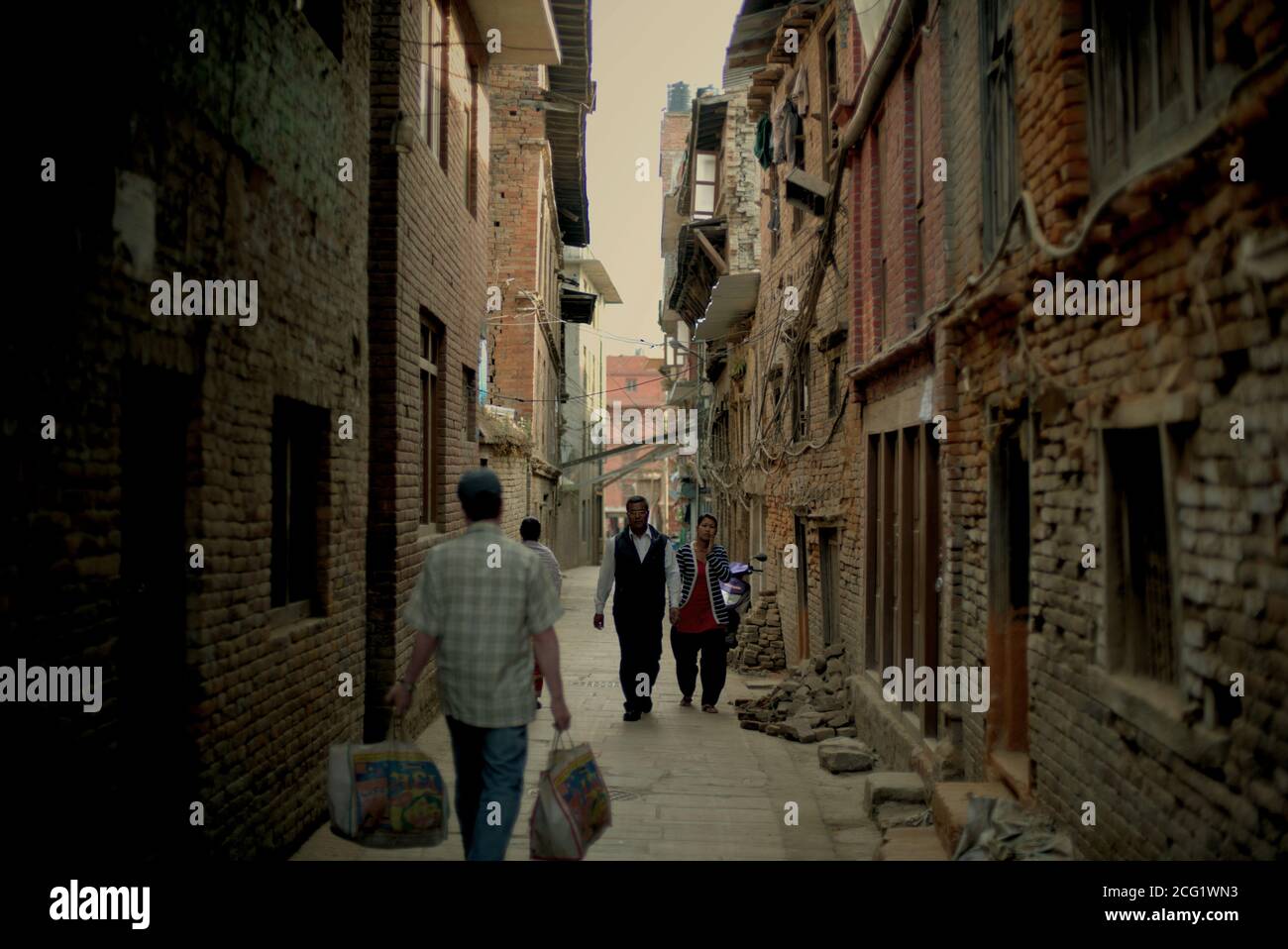People walking on a residential alley between tall bricked-houses in ...