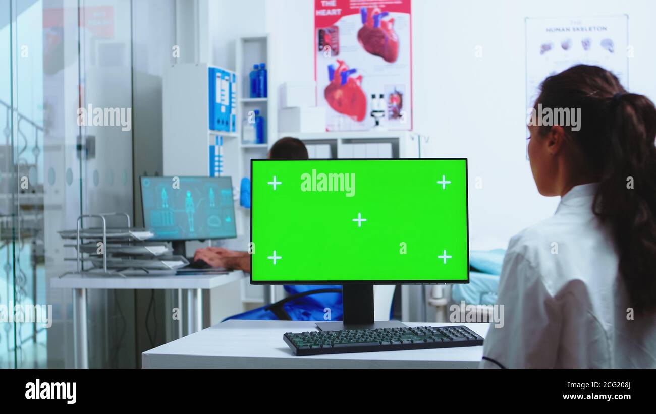 Doctor using computer with green screen mockup in hospital and ...