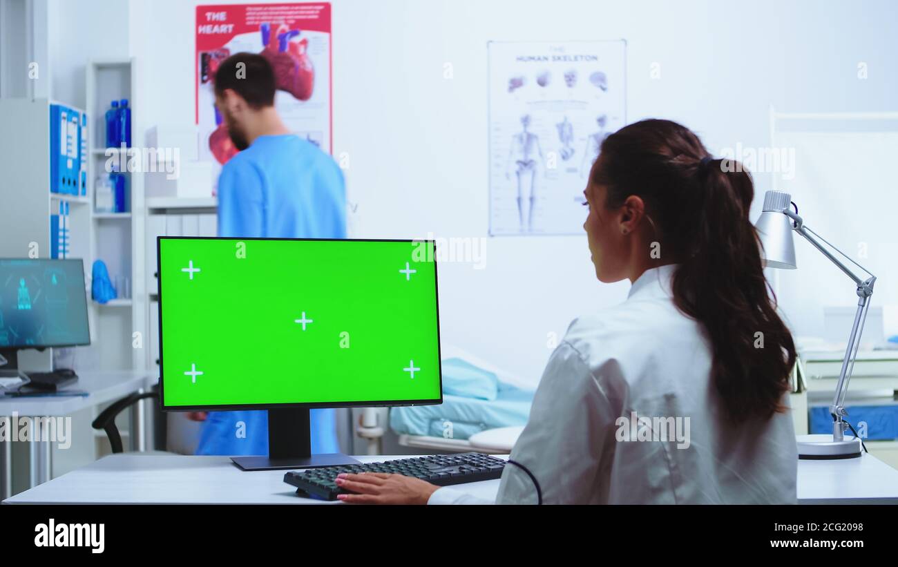 Doctor taking notes on computer with chroma key green screen and nurse ...
