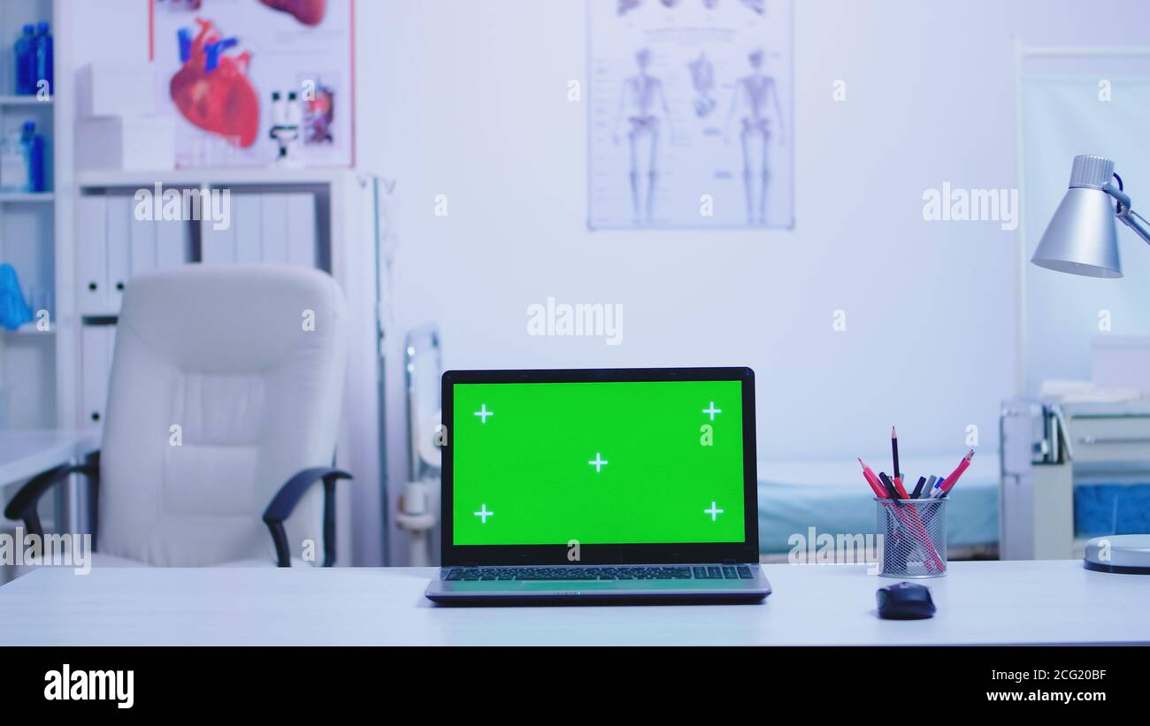Laptop in hospital cabinet with green screen and nurse wearing blue ...