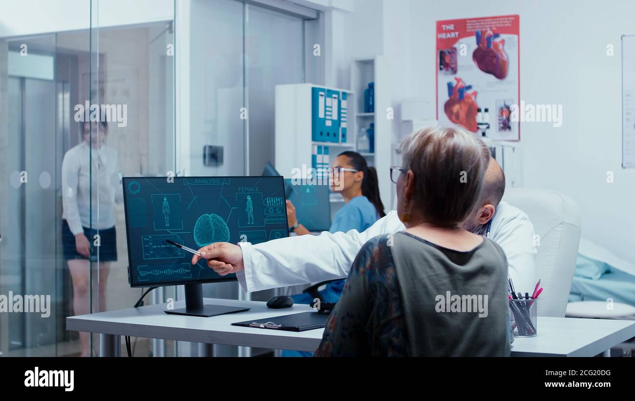 Doctor presenting futuristic medical brain scan to old retired woman ...