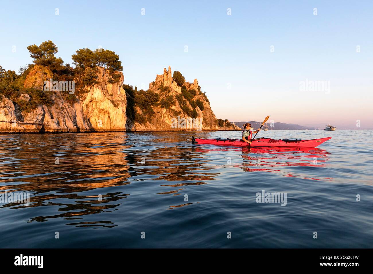 Woman in red kayak kayaking under the ruins near Duino Castle ...