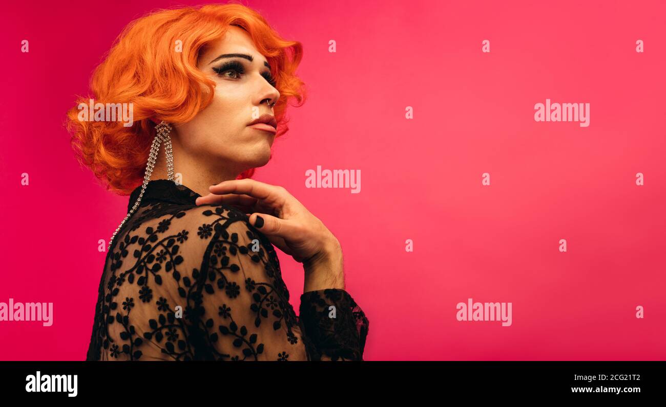 Elegant drag queen looking at copy space. Man dressed as a woman on red ...