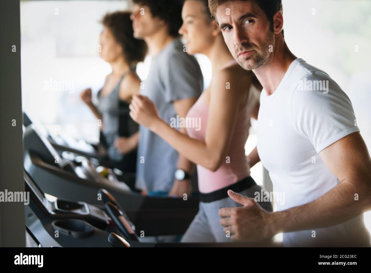 Group of young people running on treadmill in gym Stock Photo - Alamy
