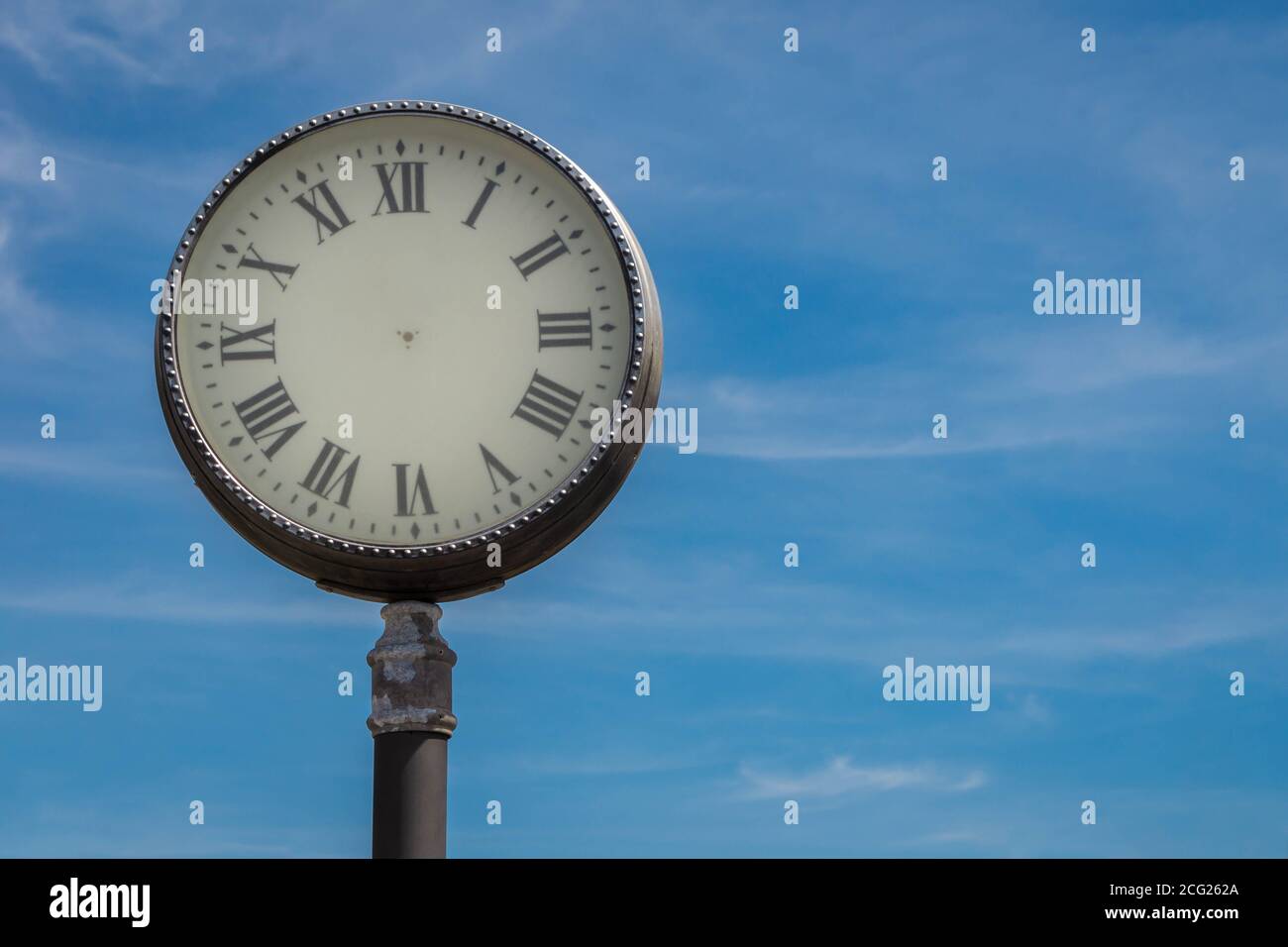 Old fashioned street clock with Roman numerals without arrows on blue ...
