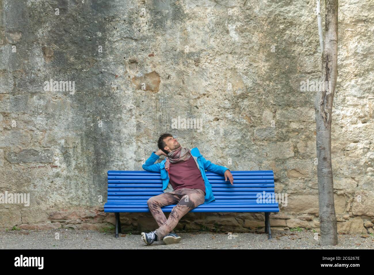 Young romantic handsome man sitting alone on bench in front ancient ...