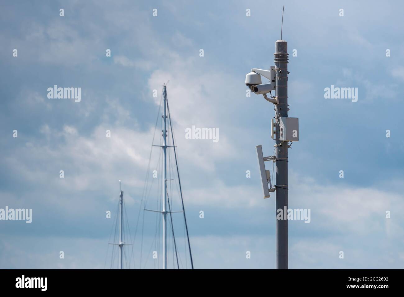 CCTV cameras installed on pole in cloudscape and yacht masts background ...