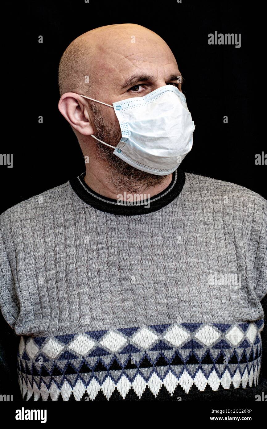 bald man on a black background in a hygienic medical mask Stock Photo ...