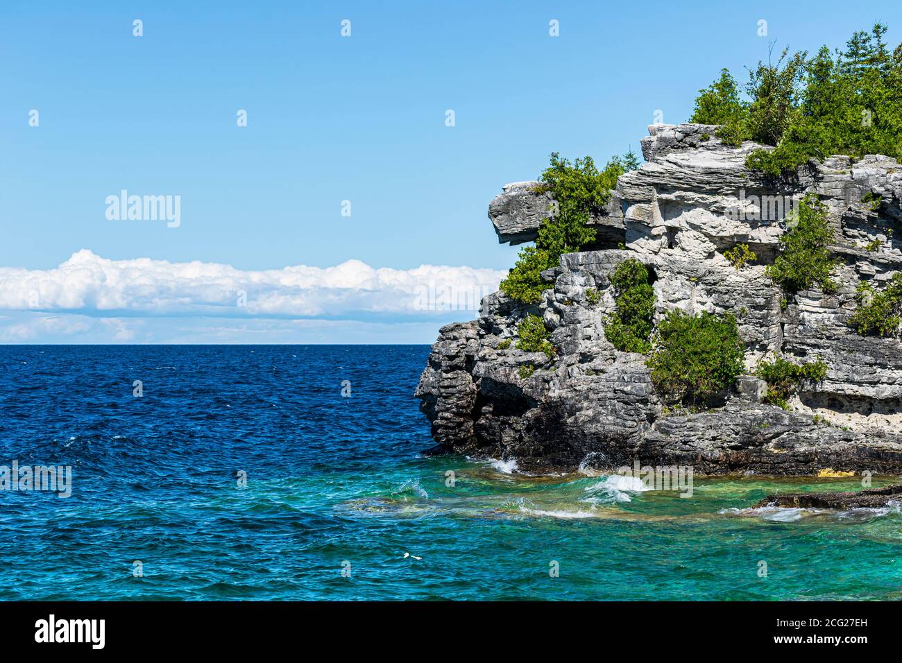 Layered rock on shoreline with waves and sky Stock Photo - Alamy