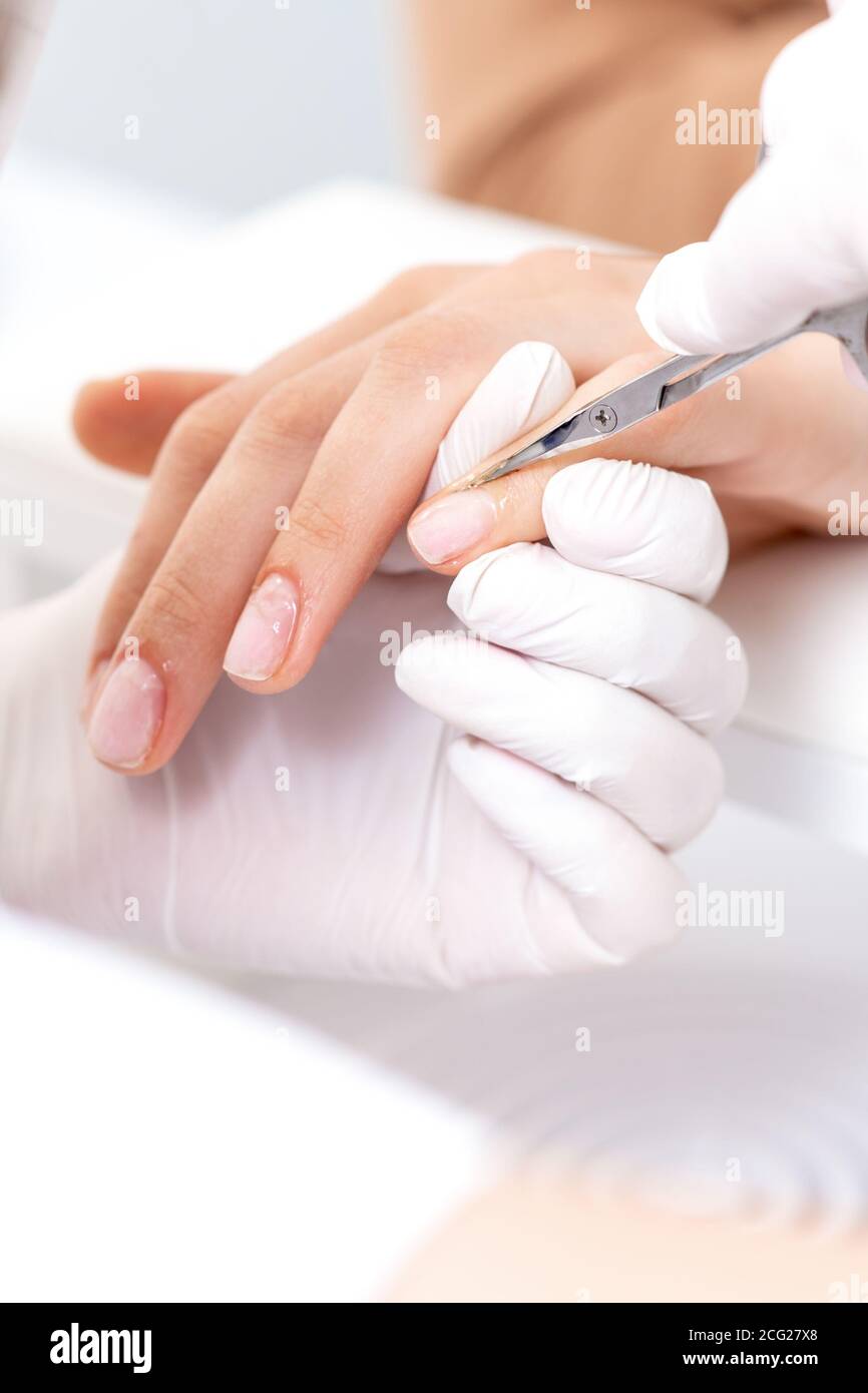 Close up of manicurist using manicure scissors to remove cuticle of ...